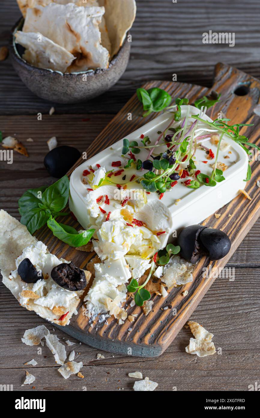 A piece of fresh feta cheese (paneer) with olives, herbs, spices and ...