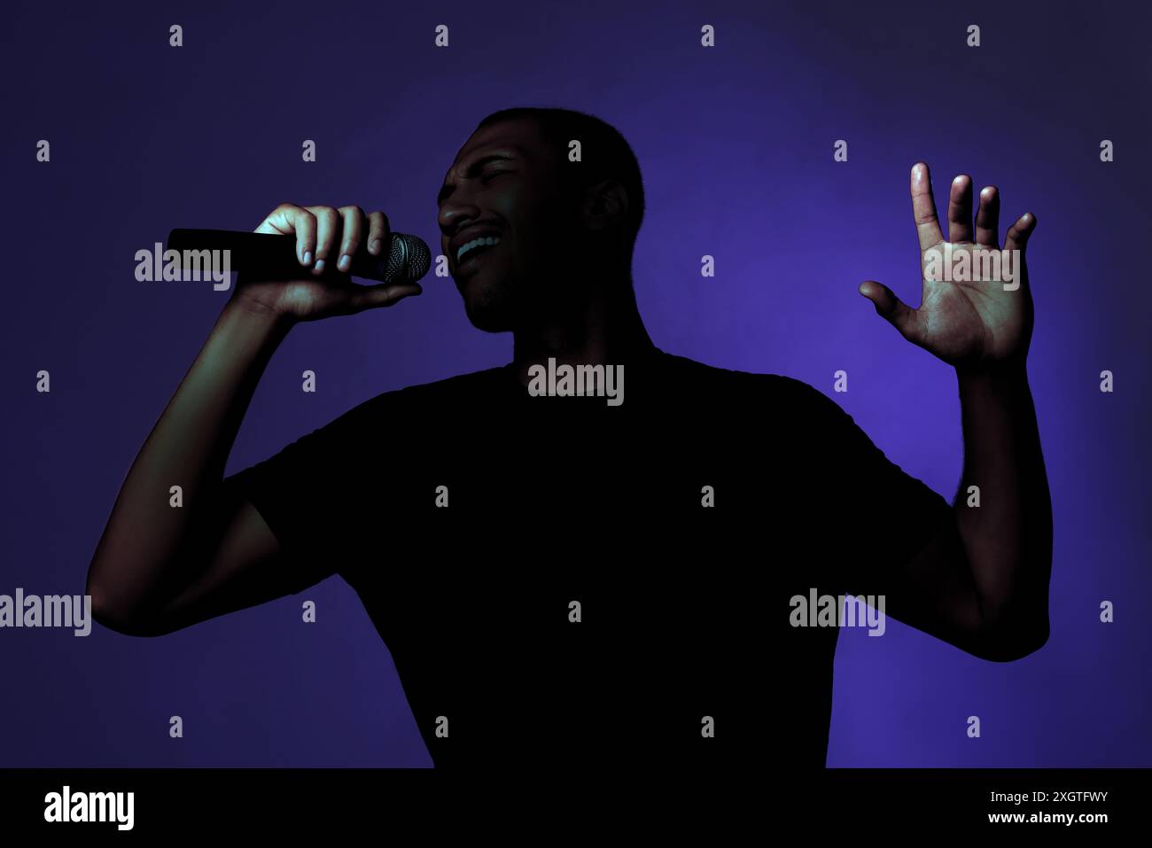 Singer performing on stage. Young man with microphone Stock Photo - Alamy
