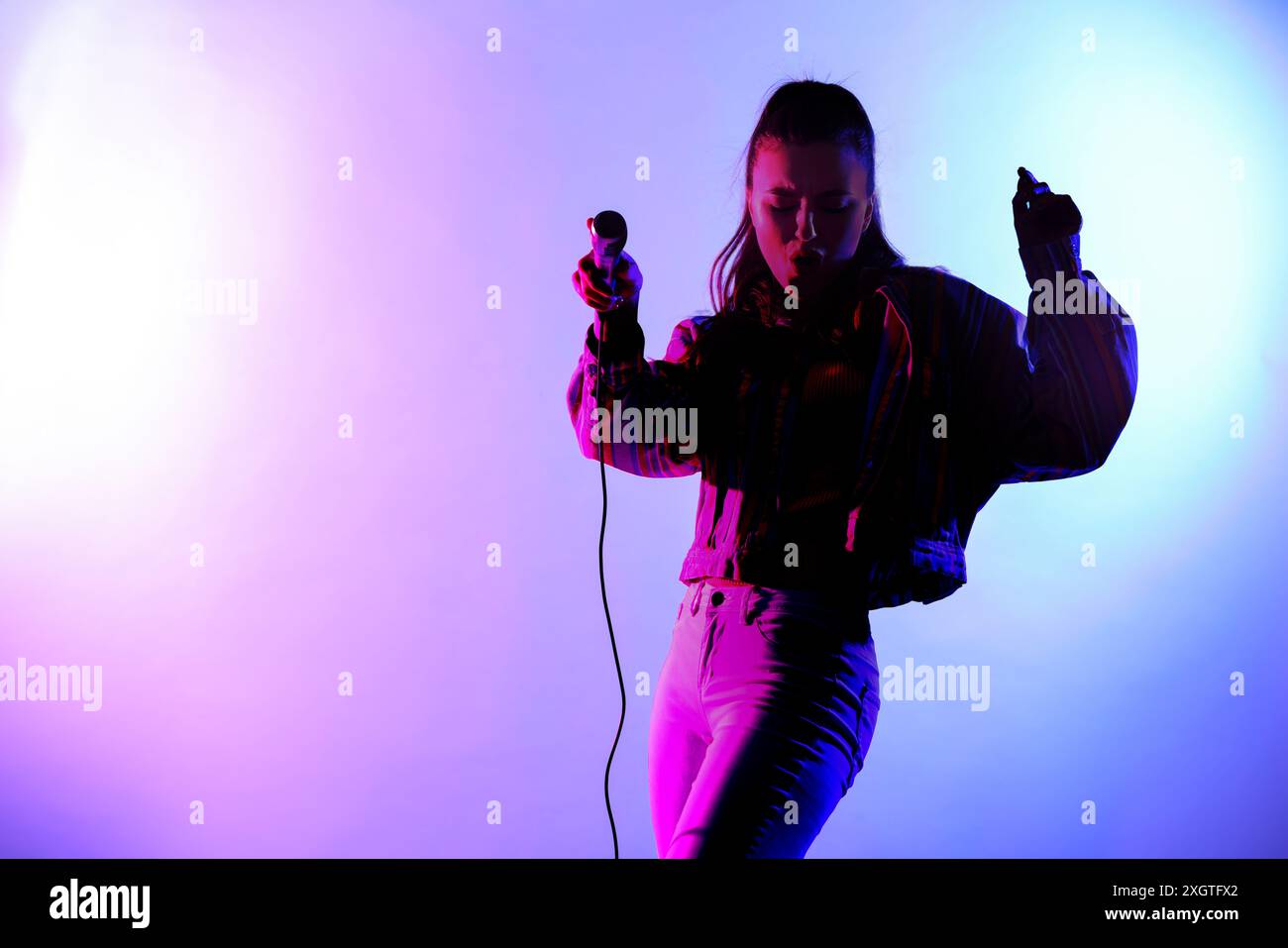 Singer with microphone in neon lights on stage Stock Photo - Alamy