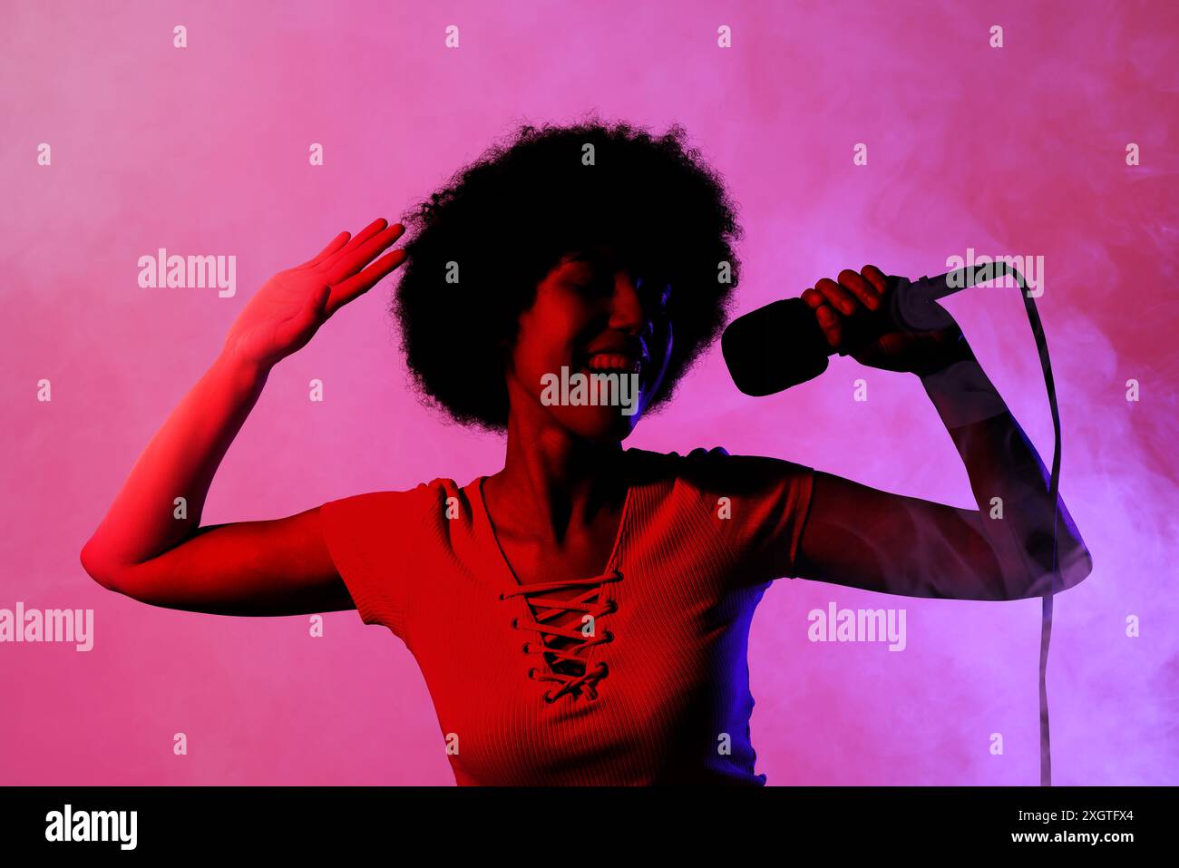Singer with microphone in neon lights on stage Stock Photo - Alamy