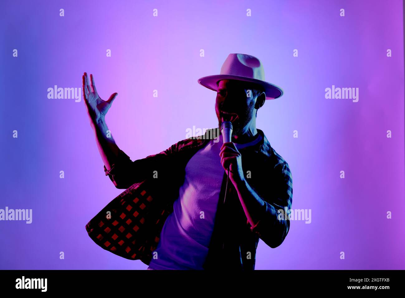 Singer with microphone in neon lights on stage Stock Photo - Alamy