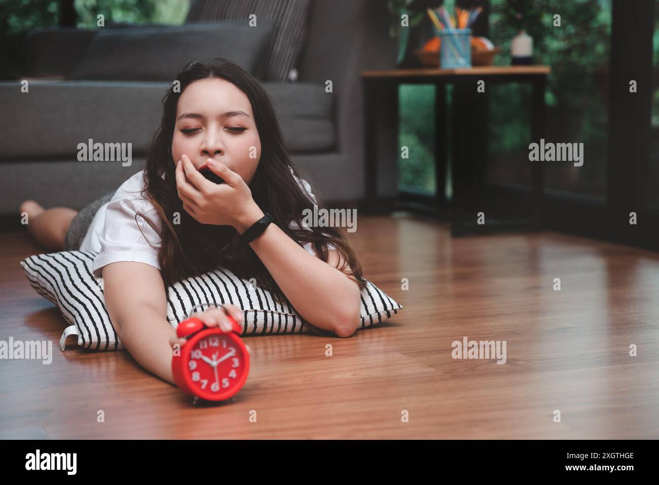 Young asian woman open mouth yawning reaching over to turning off alarm ...