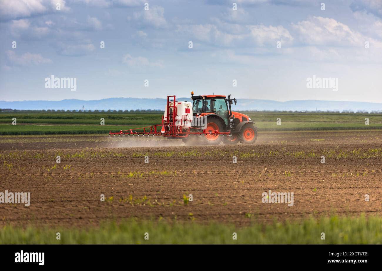Tractor spraying pesticides on field with sprayer Stock Photo - Alamy