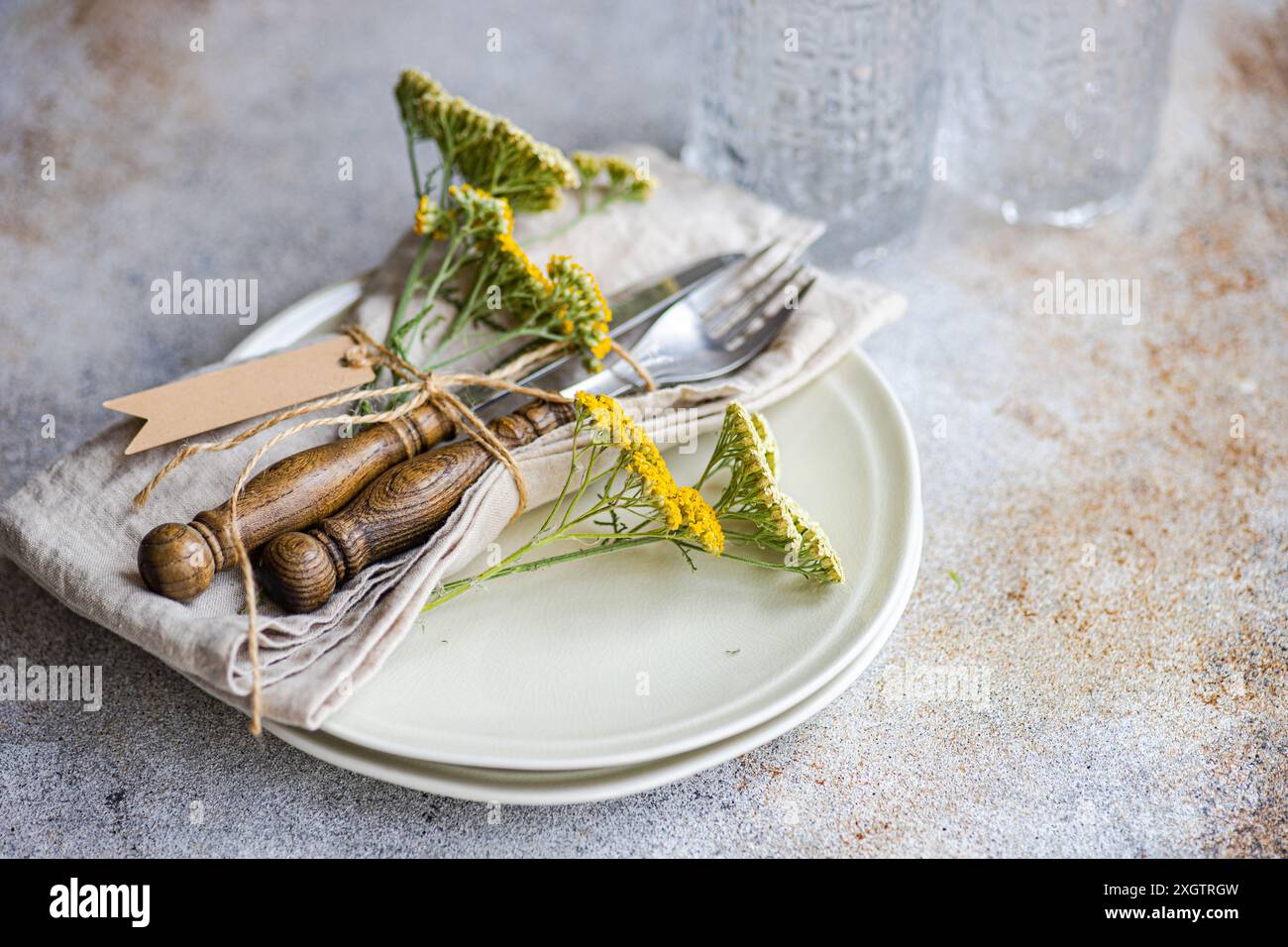 A warm and inviting rustic table setting featuring a simple cream plate, vintage silverware, and ...