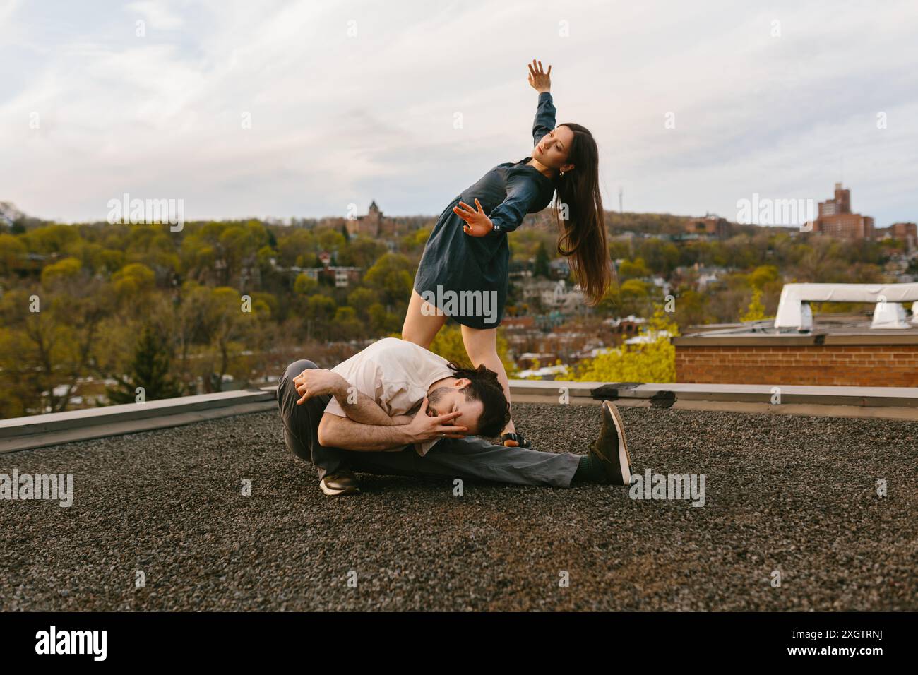A man and woman perform a dynamic dance pose on a rooftop, with a ...