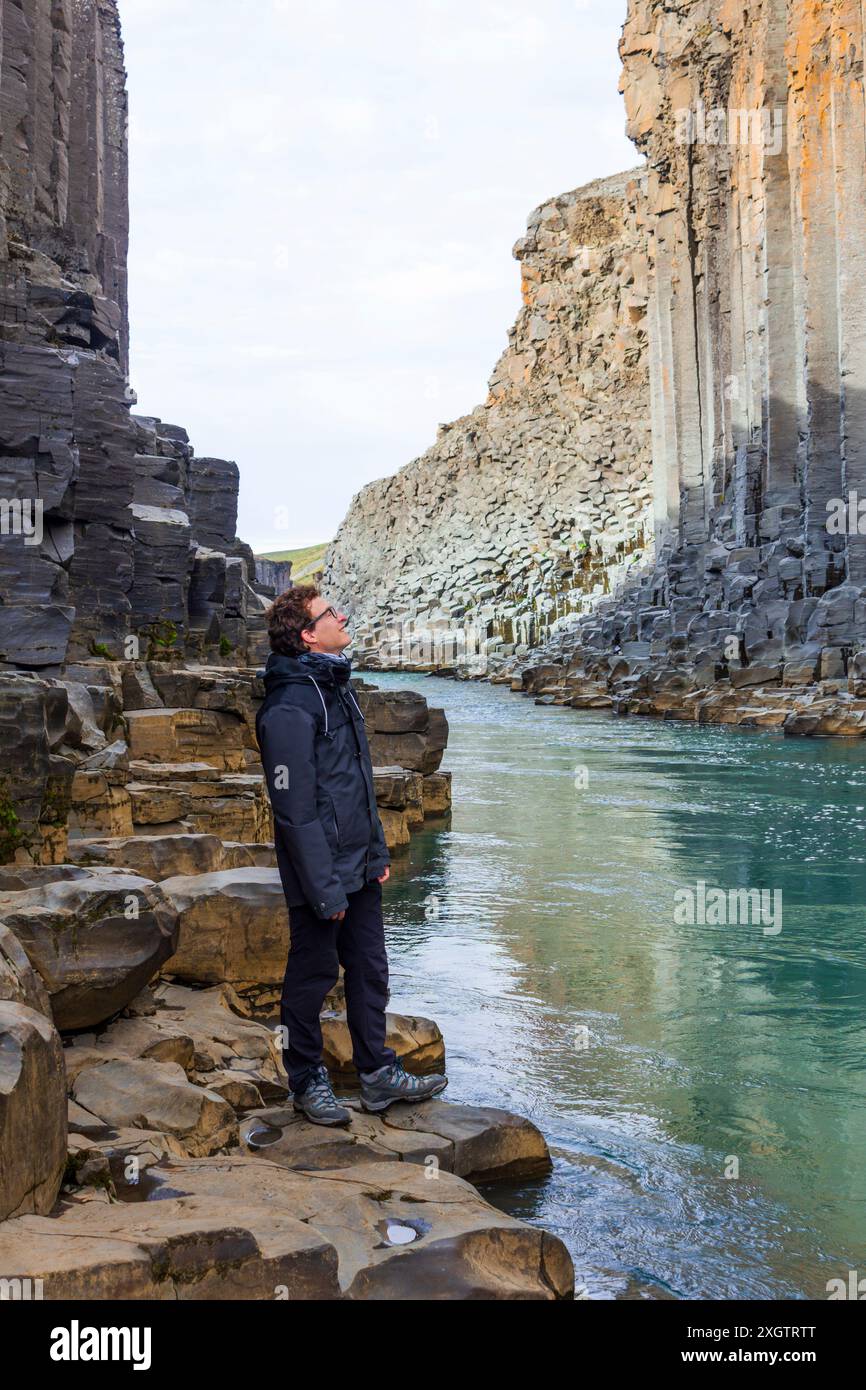A man stands awestruck by the stunning basalt columns and serene river ...