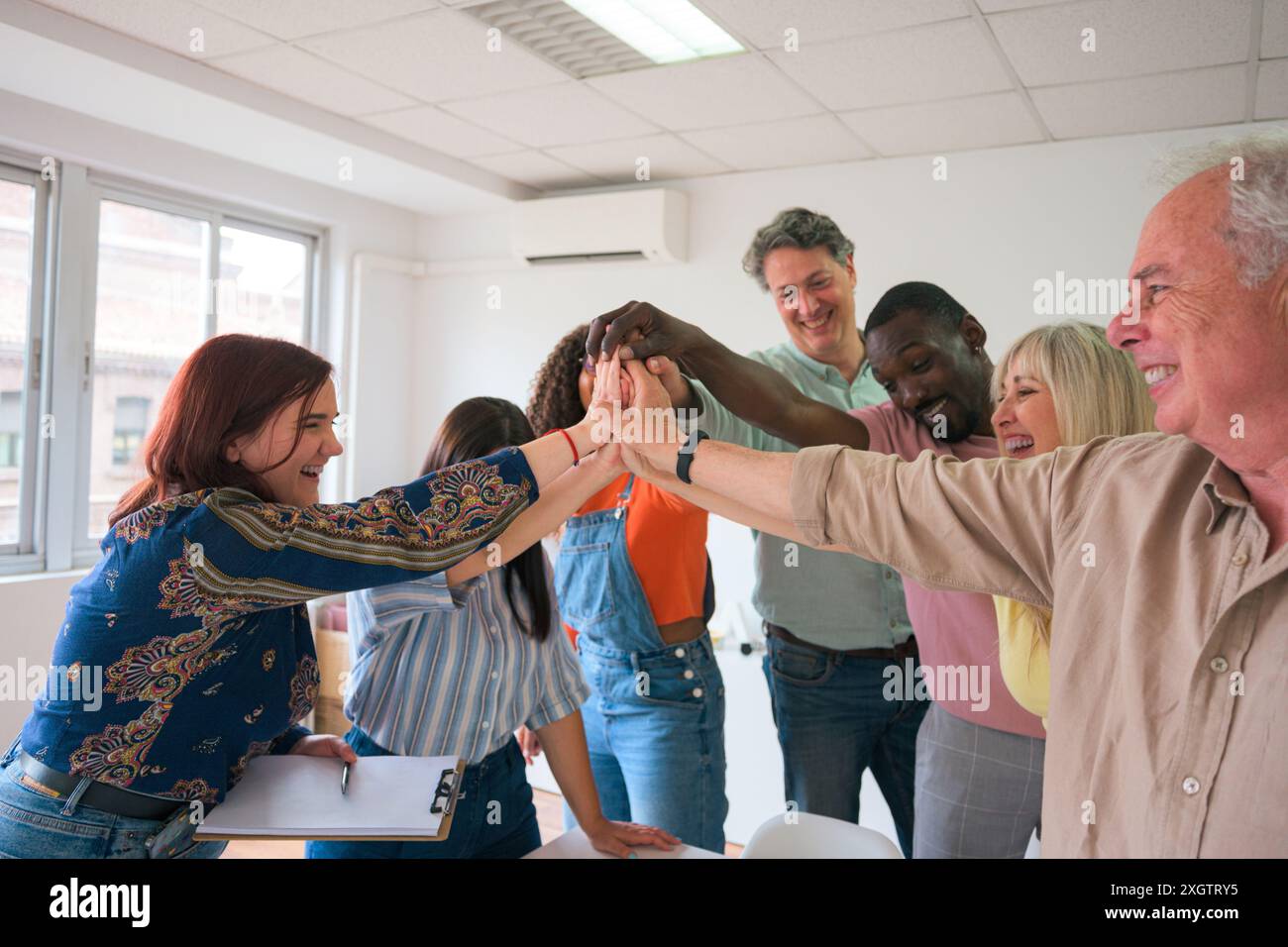 A group of diverse colleagues happily celebrating a success in a well ...