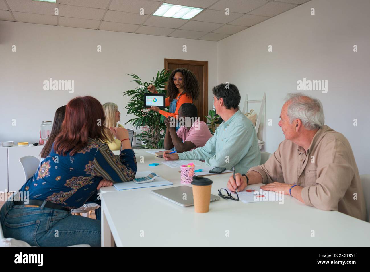 A diverse group of professionals gather around a table in a brightly ...