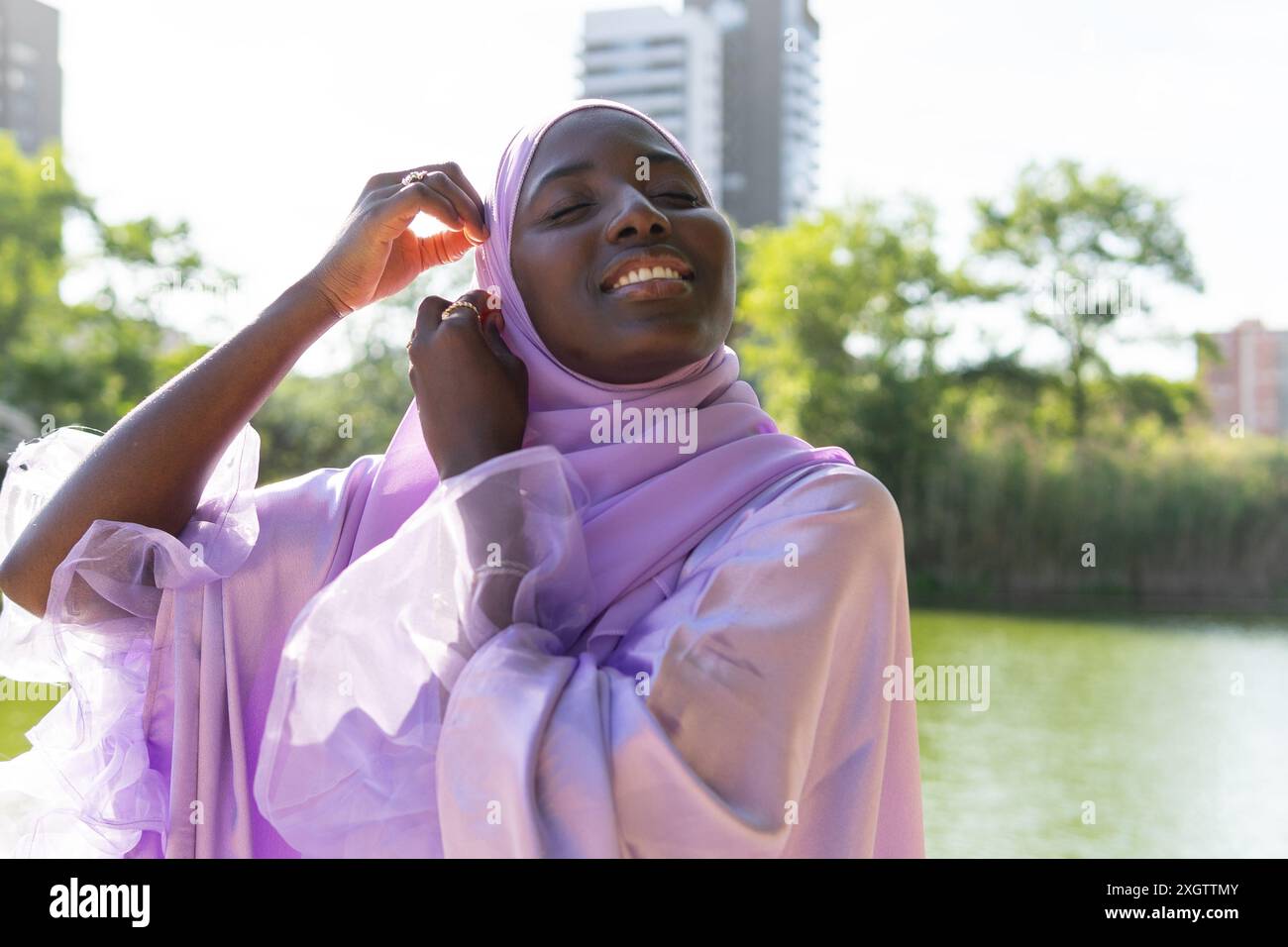 Radiant Muslim woman dressed in purple hijab, smiling joyfully in a ...