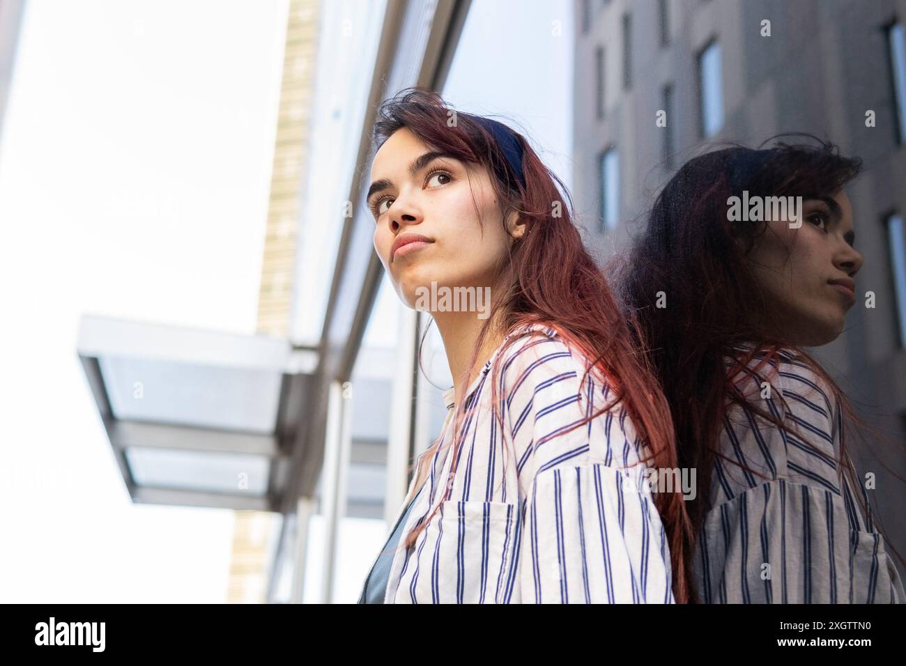 An introspective young woman with flowing hair looks upward, her image ...