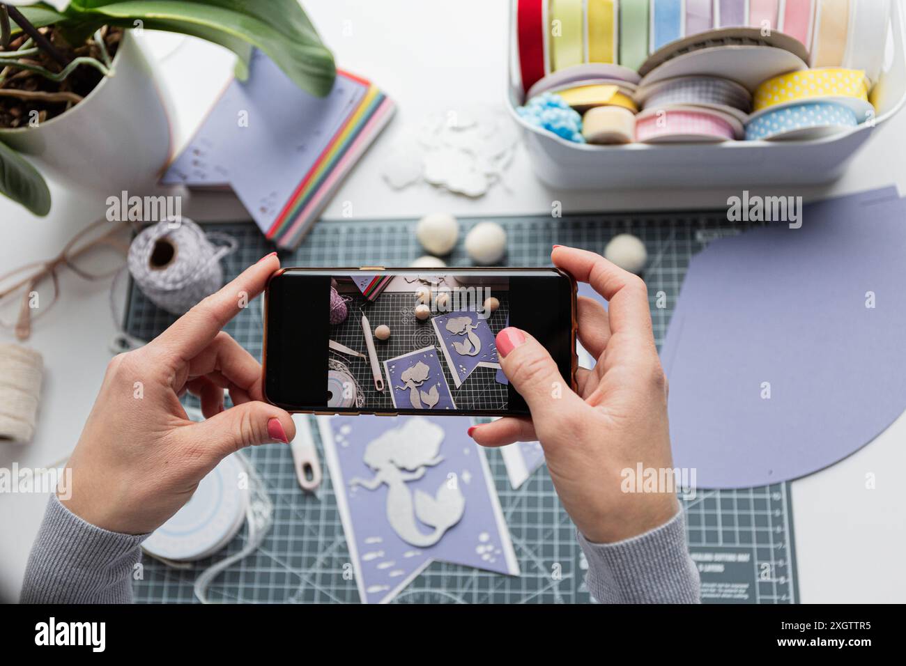 Anonymous young woman uses her smartphone to photograph her creative ...