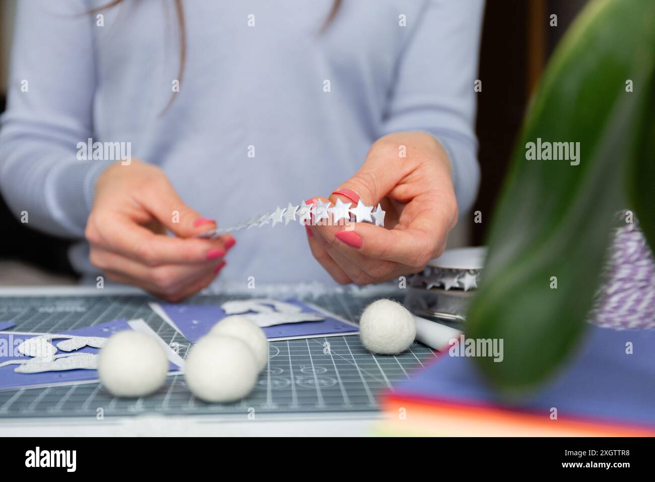 Anonymous young woman is focused on making a charming paper craft ...
