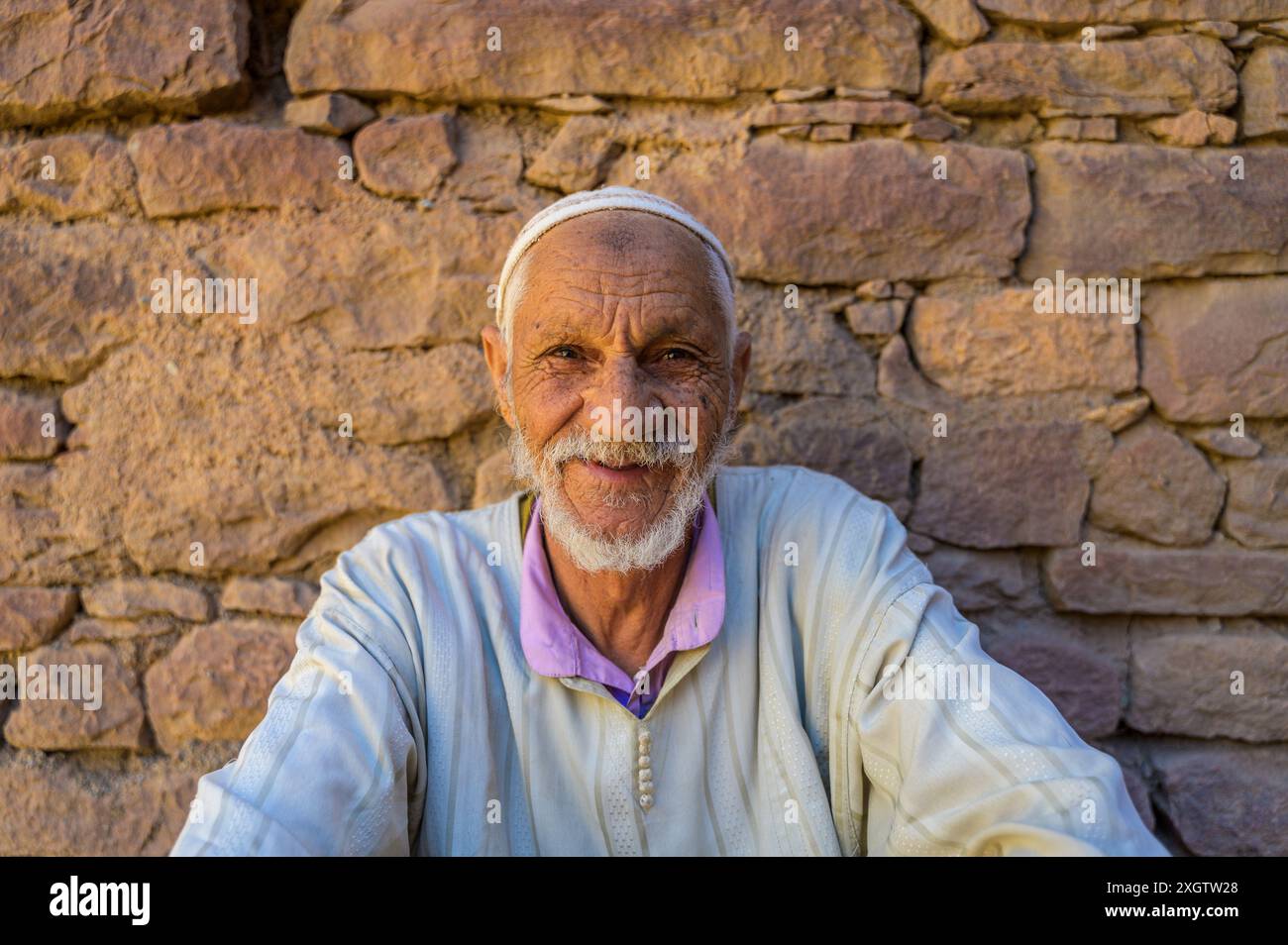 A joyful elderly Moroccan man with a warm smile pictured sitting ...