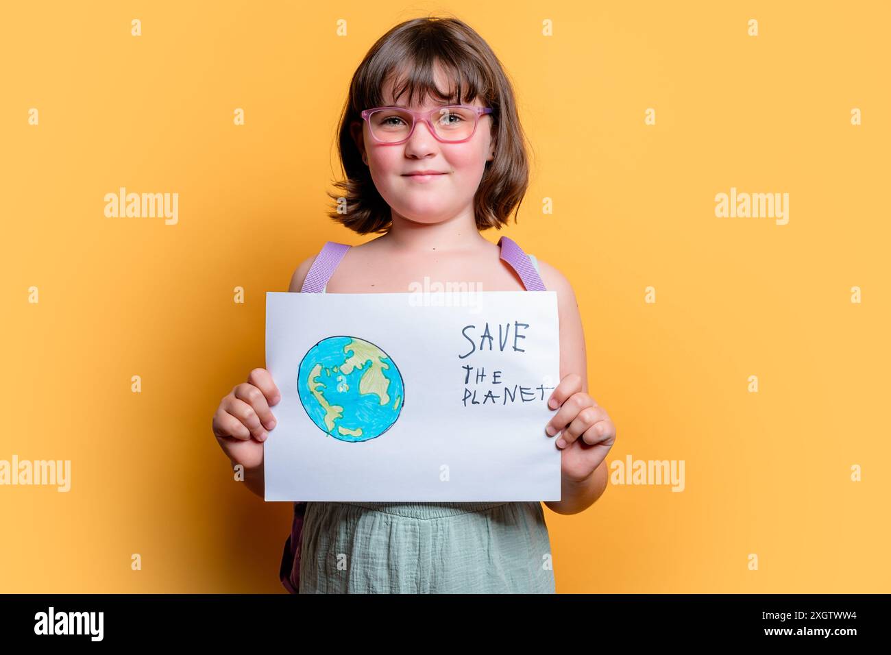 A young Caucasian girl confidently presents a handwritten Save the ...