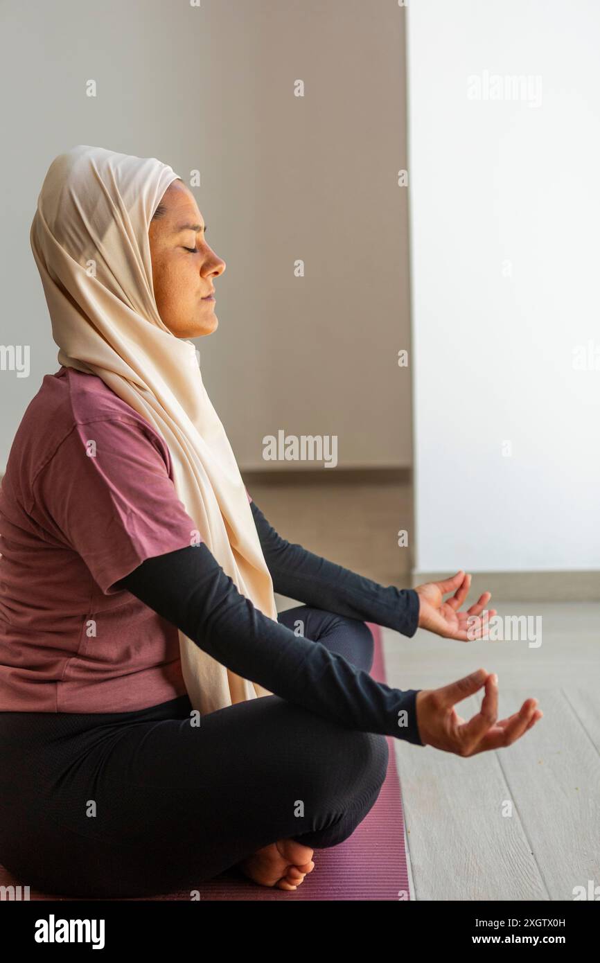 Side view of a Muslim Arab woman, eyes closed, is engaged in a yoga ...