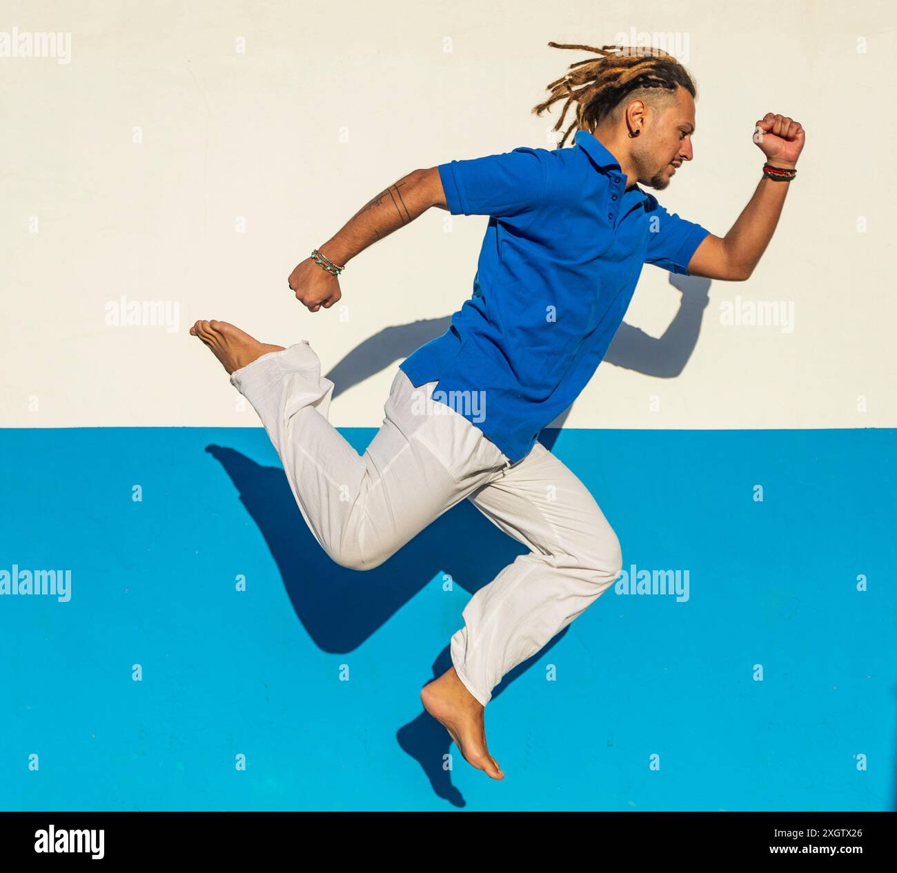 Side view of a caucasian male dancer with dreadlocks is captured mid ...