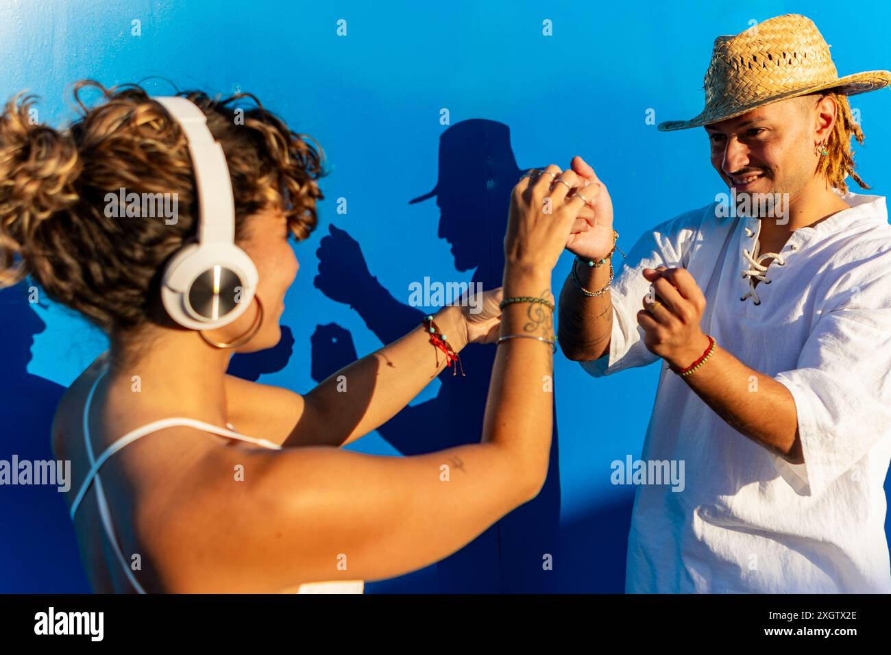 A Caucasian man and woman dance a joyful hand-clapping game against a ...