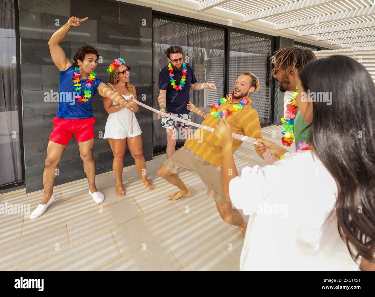 A diverse group of friends partakes playing game during a summer party ...