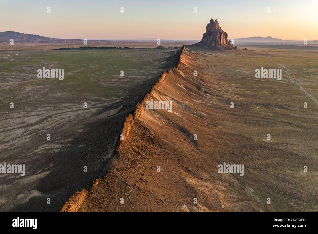 Sunset casts warm hues over the iconic Shiprock formation and the vast ...