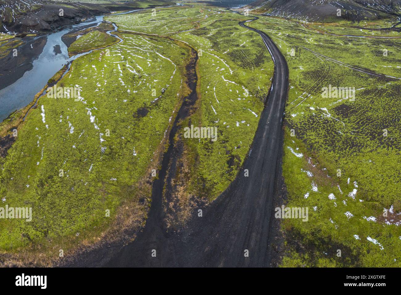 An aerial view captures a winding road slicing through the lush, green ...