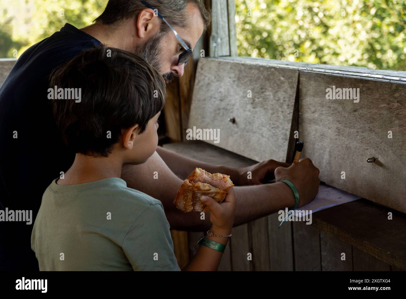 Side view of a father and son duo participate in bird watching inside a ...