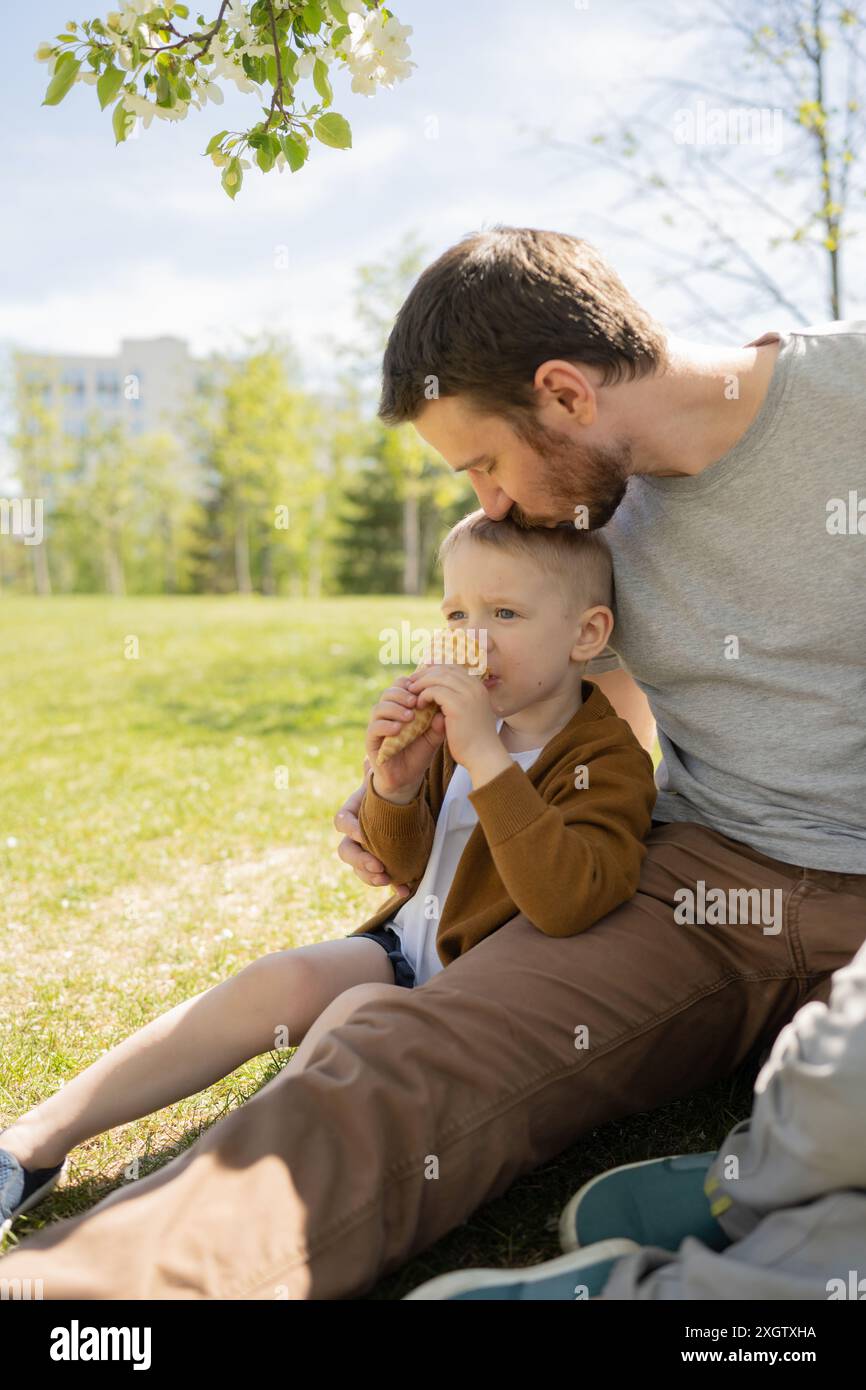In this heartwarming summer scene, a father and his preschool son sit ...