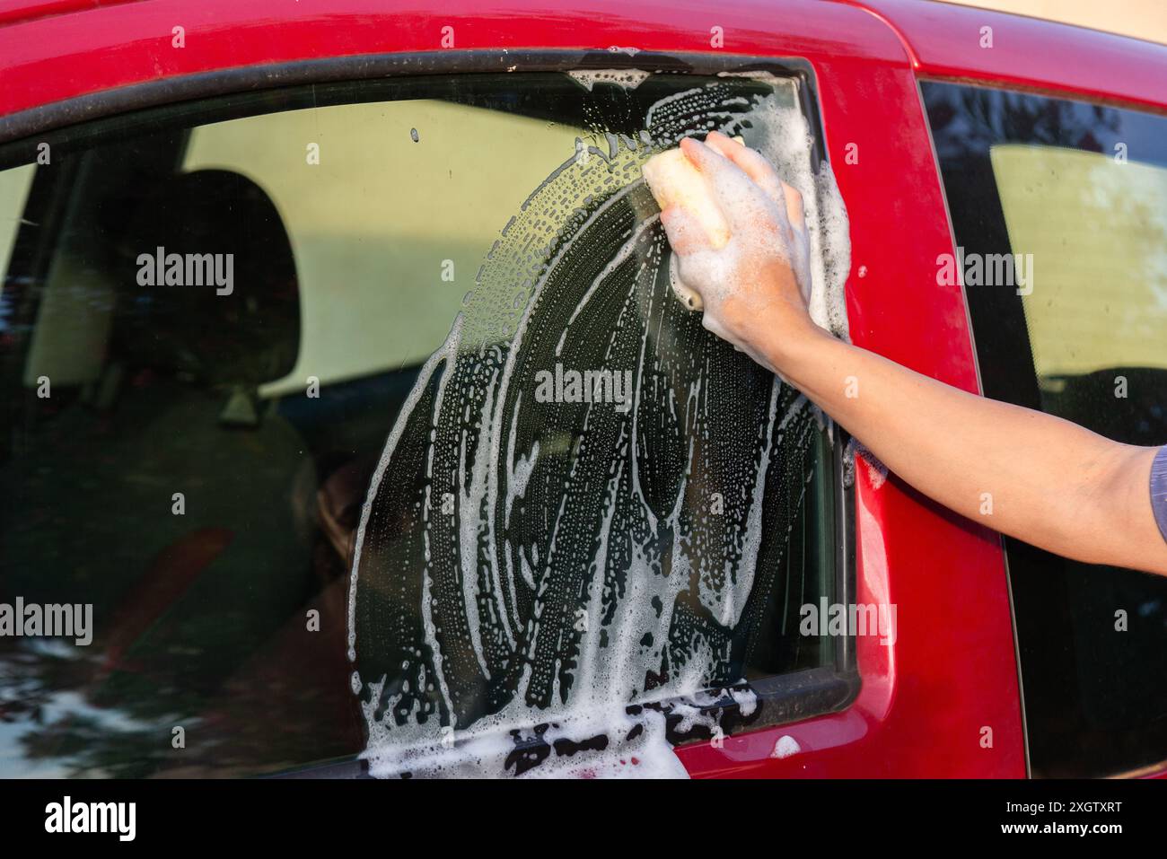 Close-up of a person's hand scrubbing a car window with soapy water ...