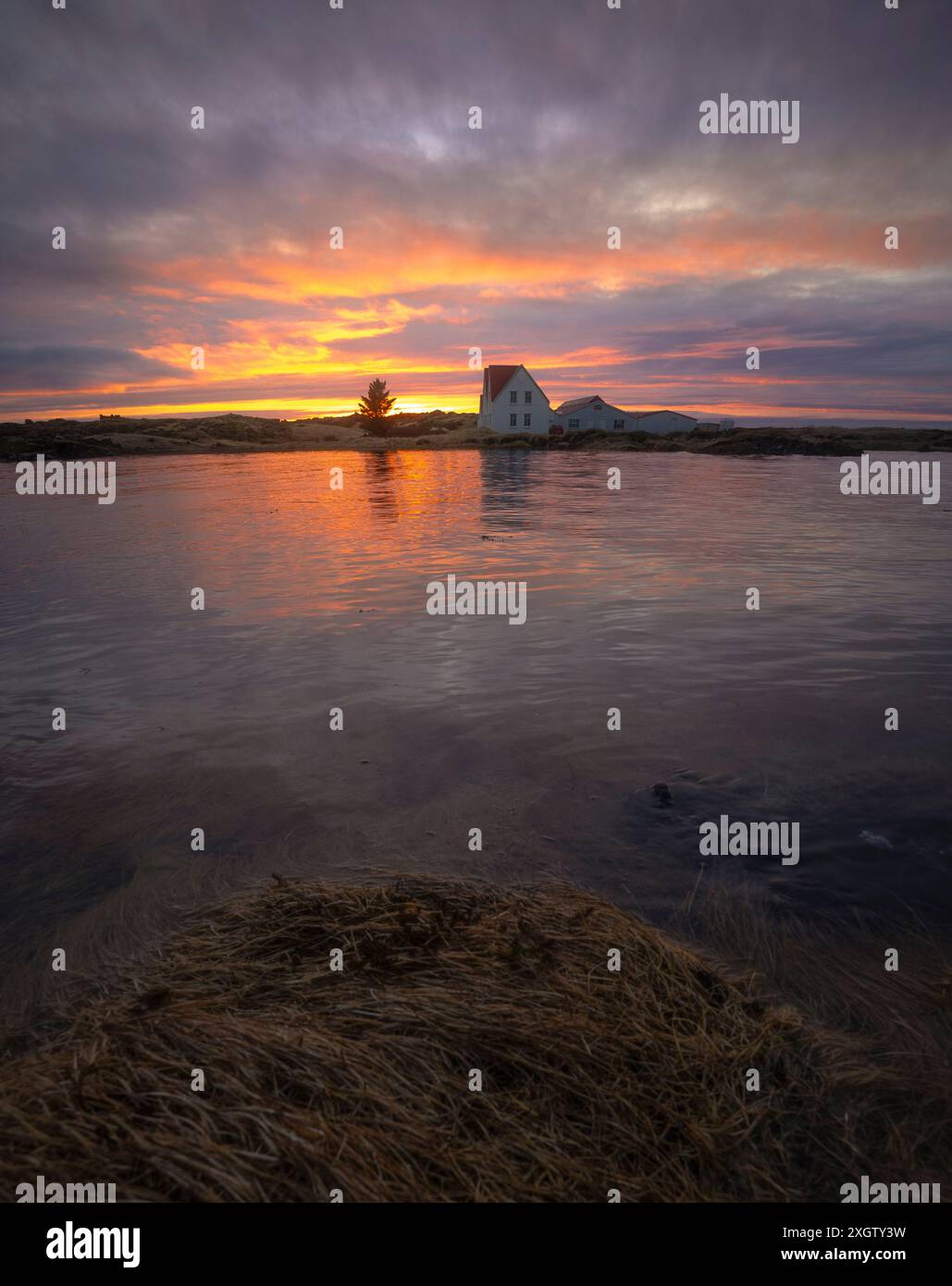 An idyllic house in Iceland sits quietly by a river, bathed in the warm ...