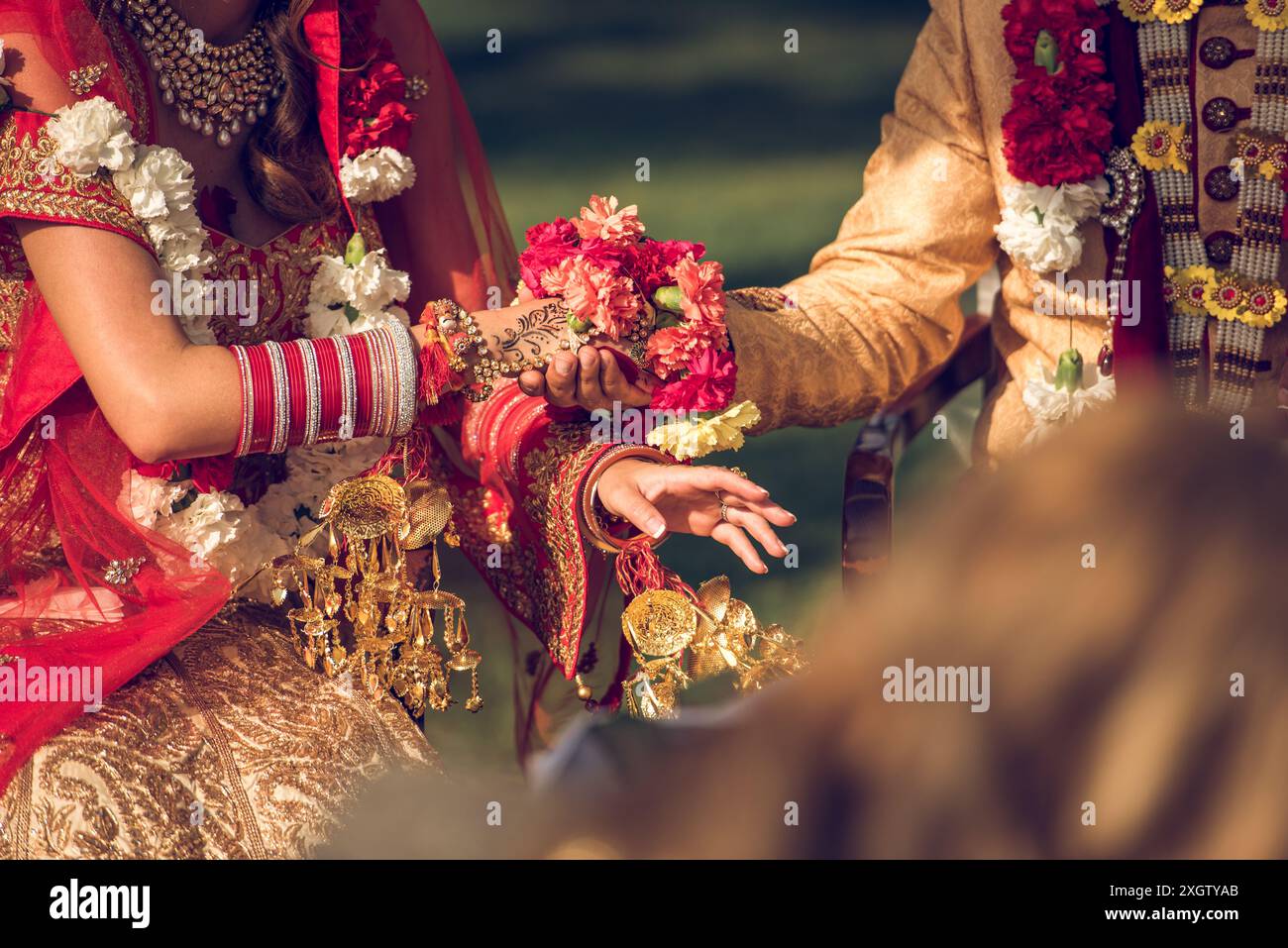 Traditional Indian wedding with crop unrecognizable bride and groom exchange floral garlands ...
