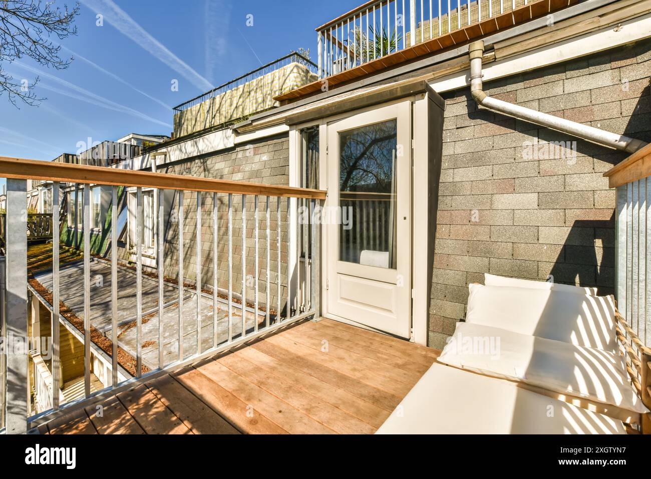 Sunlit rooftop balcony featuring comfortable seating, wooden floor, and ...