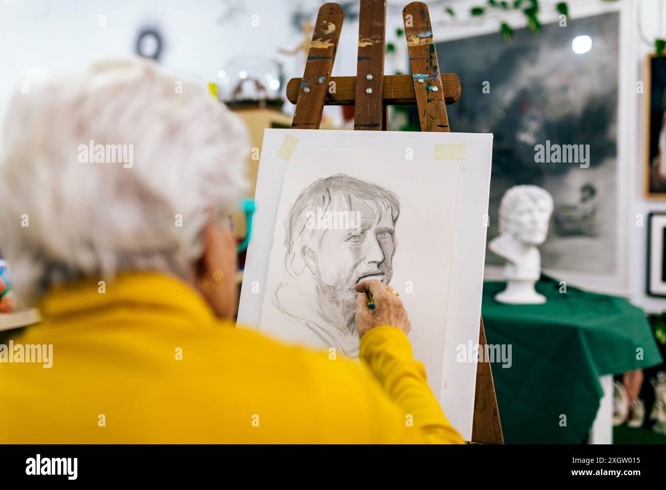 Anonymous senior woman engages in drawing a male portrait on a canvas ...