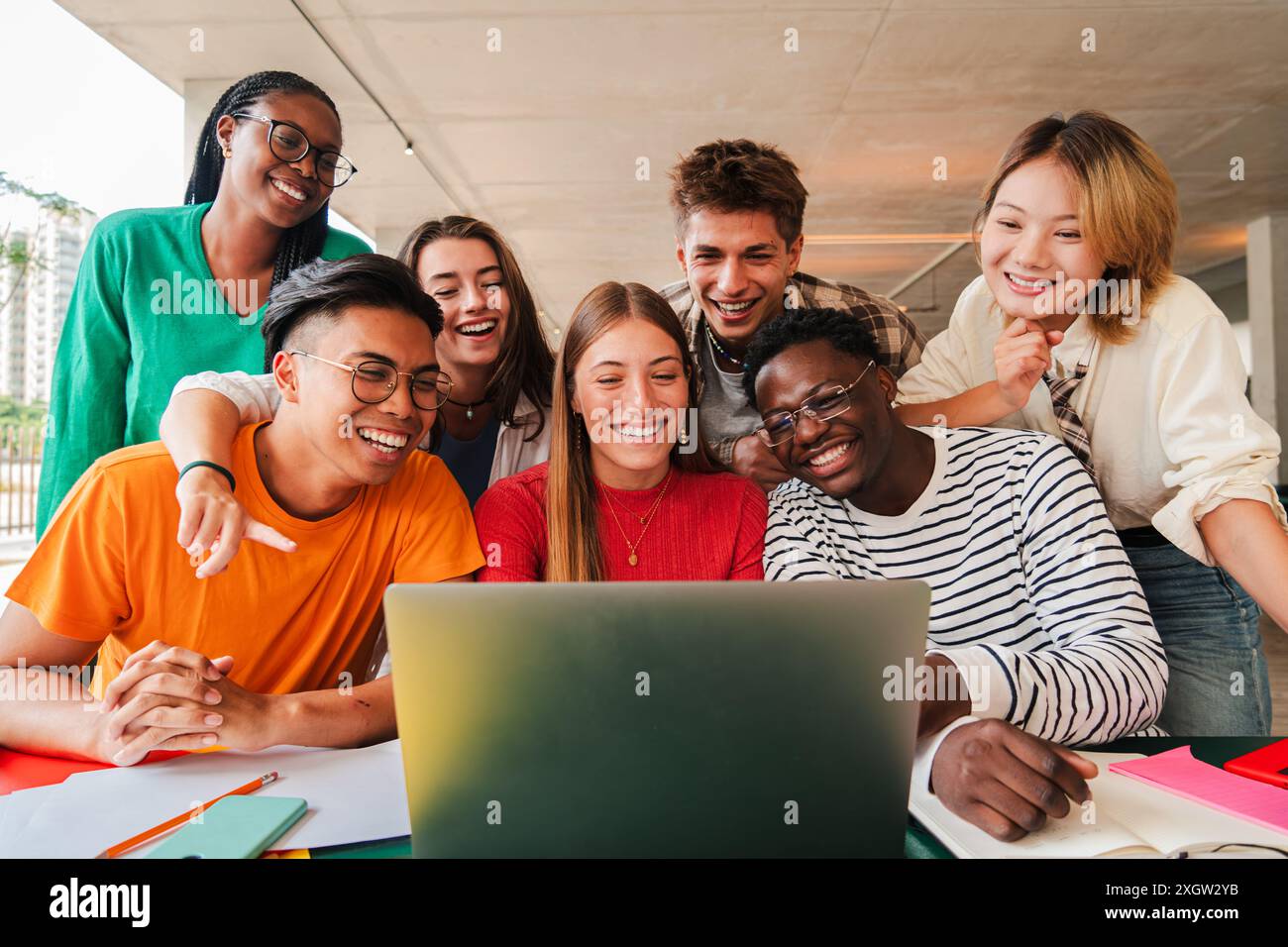 Big group of young students using a laptop to do the homeworks at high ...