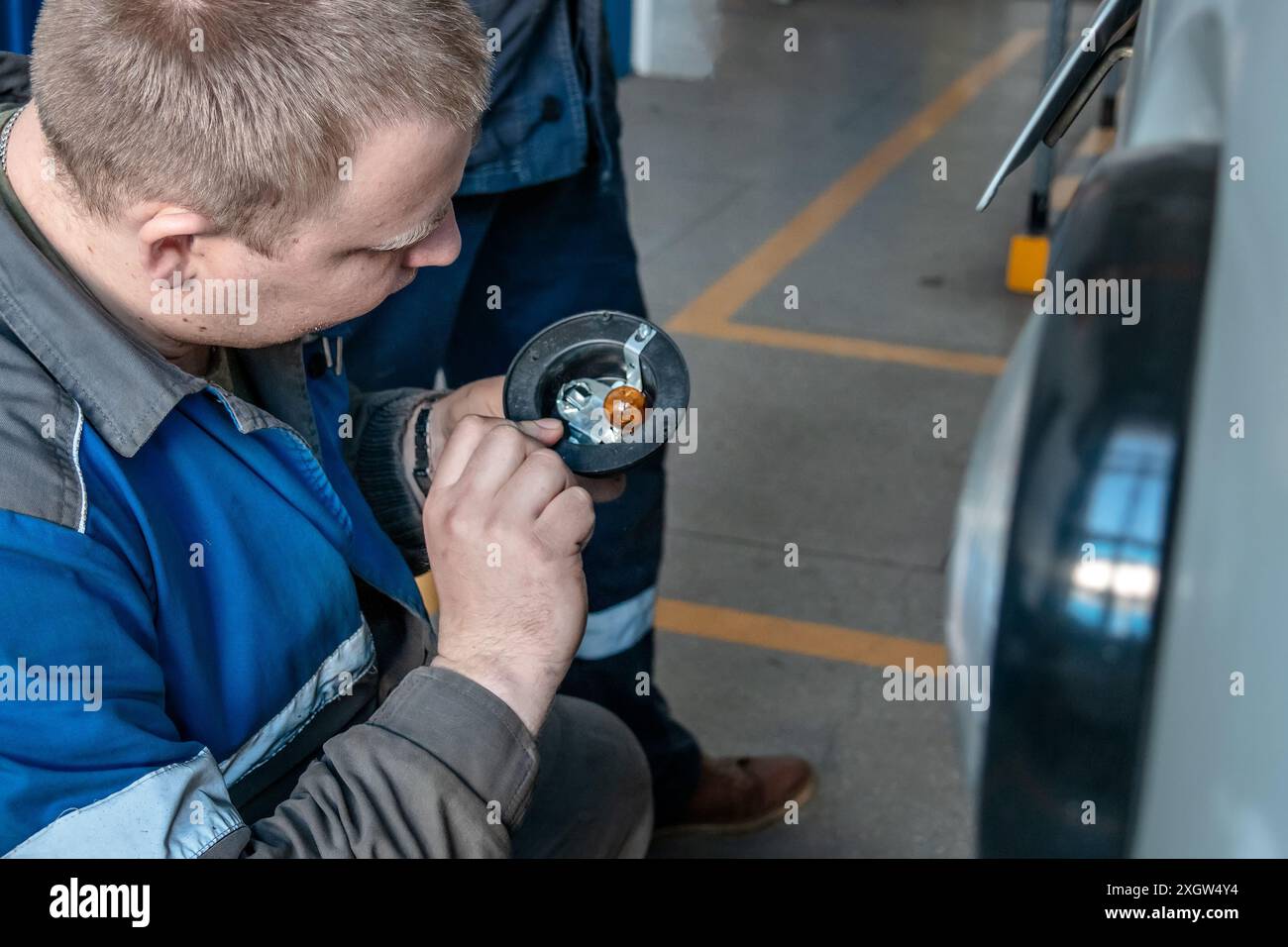 A worker repairs a broken indicator light on a vehicle, examining the ...