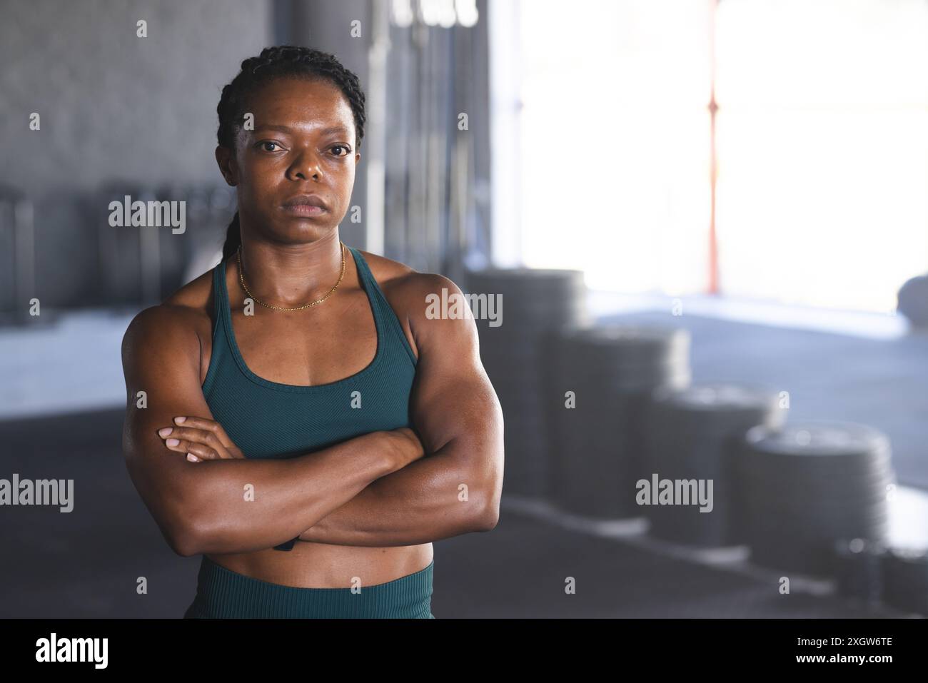 A fit African American woman stands in gym with a blue background. Her ...