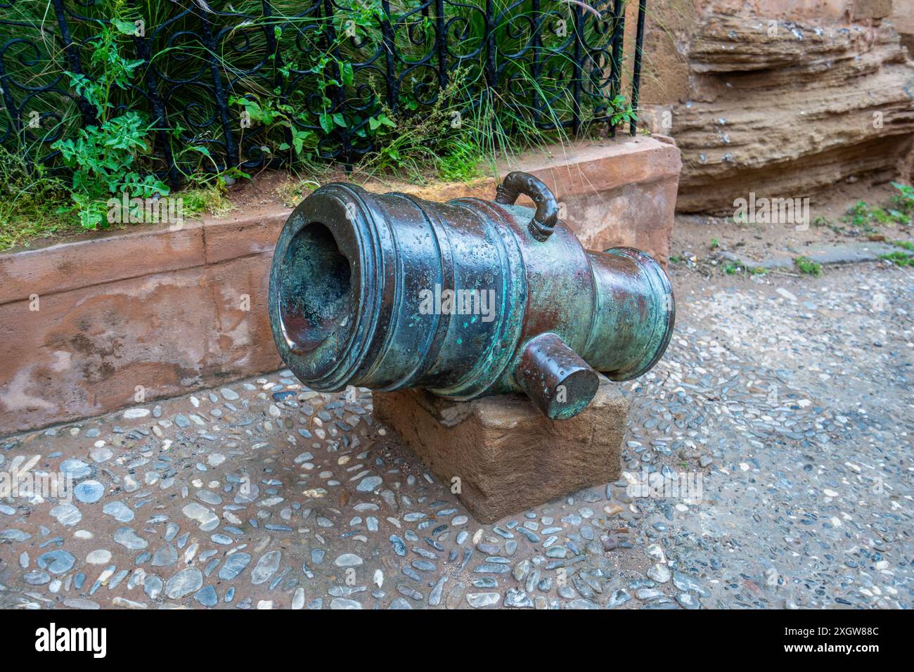 Verdigris-covered cannon on stone pedestal by Kasbah wall. Historical ...