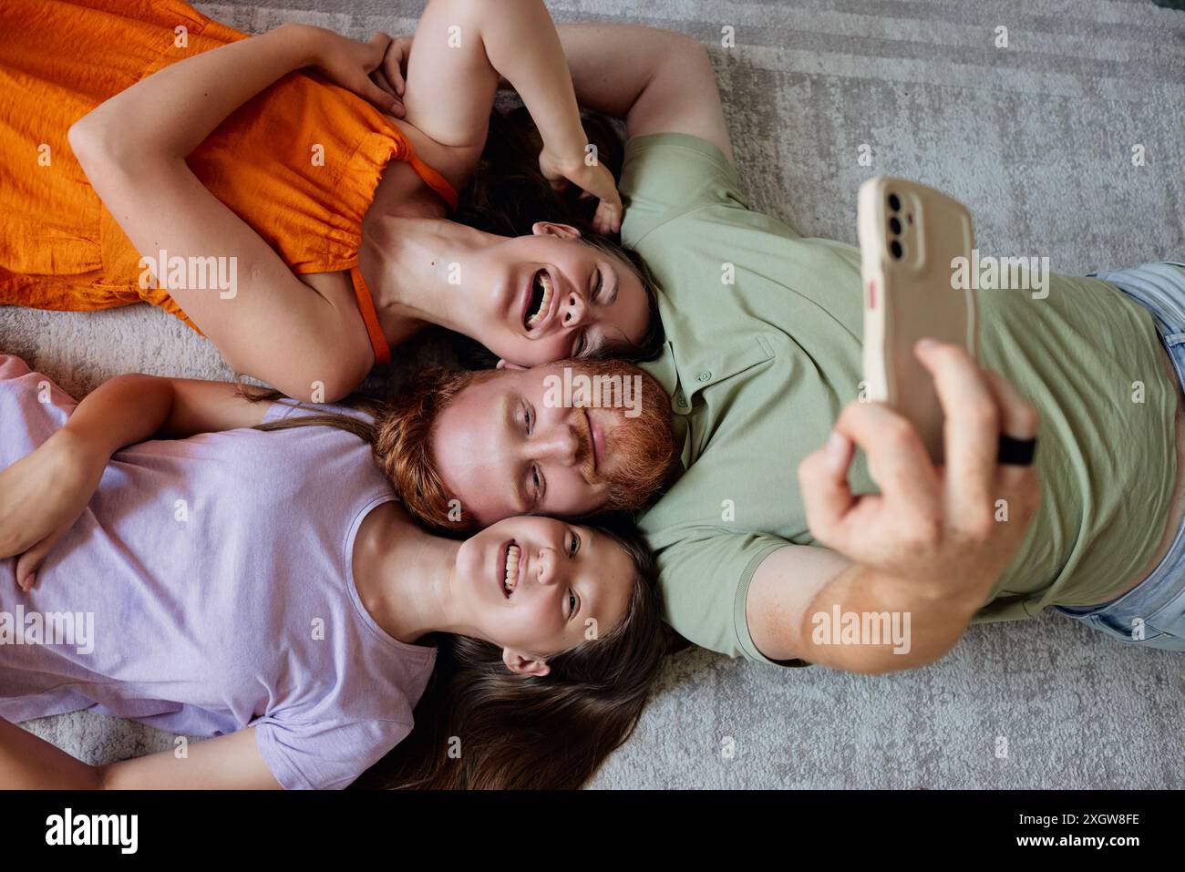 Three friends lay on their backs on the floor, their heads forming a ...