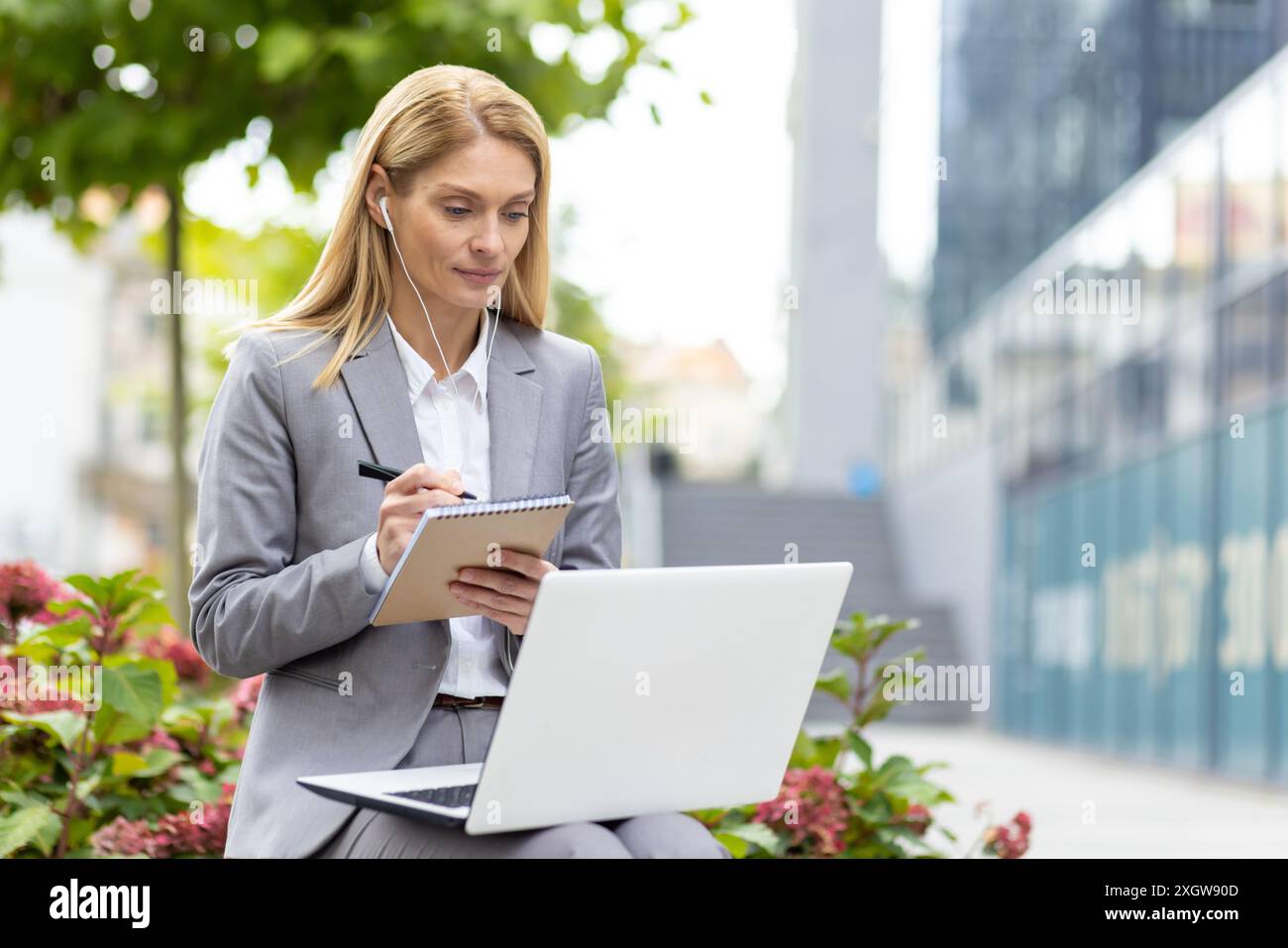 Professional businesswoman multitasking outdoors, writing notes on a ...
