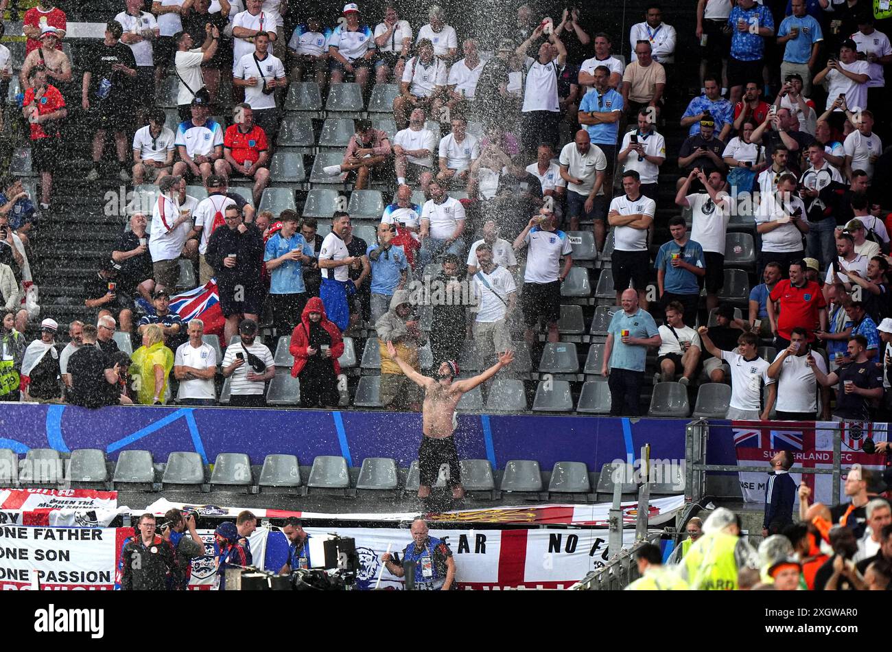 A fan bathes in rainwater falling from the stadium roof ahead of the ...