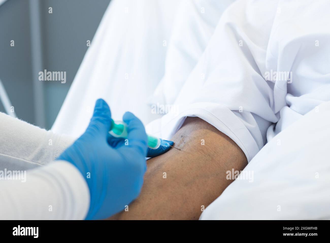 Nurse administers an injection to a patient in a hospital. The focus is ...