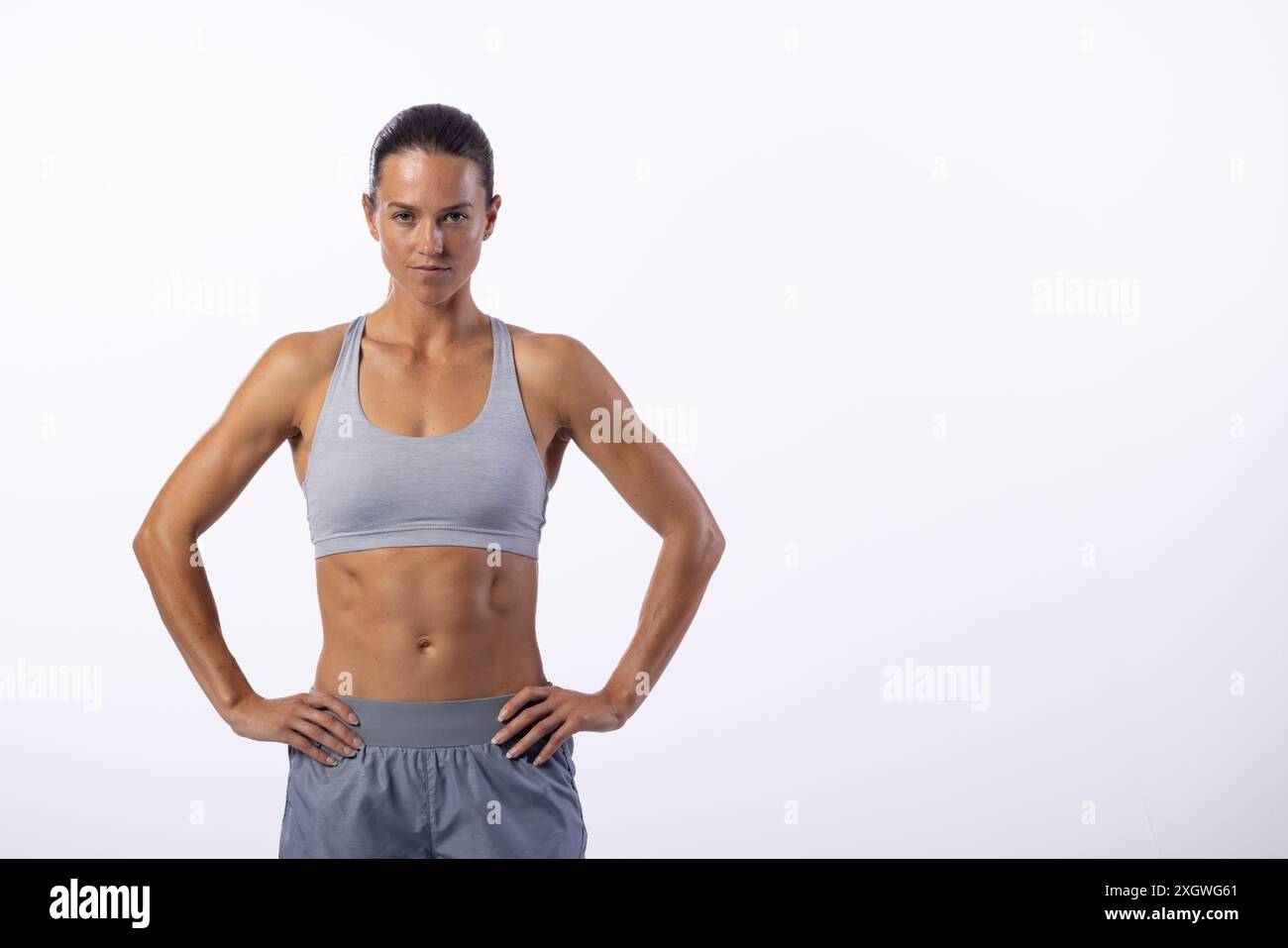 A confident young Caucasian female athlete poses, white background ...