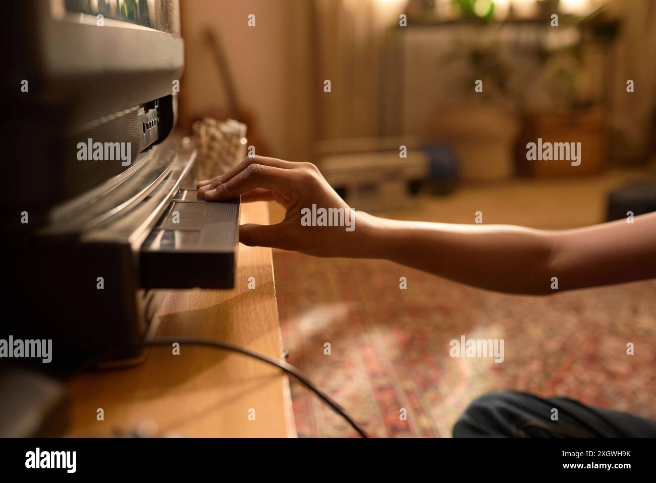 Close-up of hand inserting VHS tape into old-school VCR player standing ...