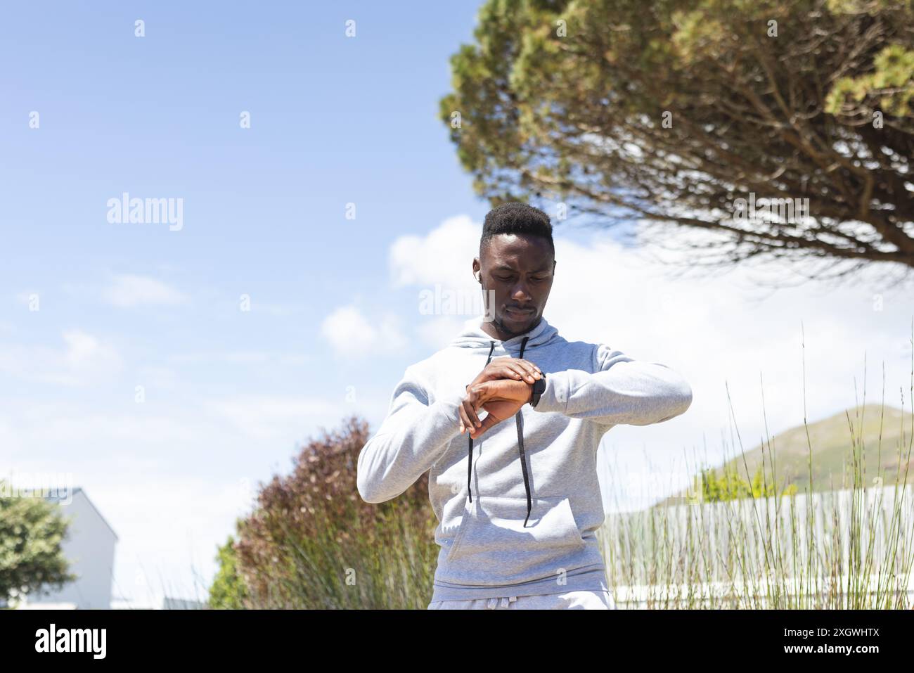 Happy african american man wearing hoodie and earphones running and ...