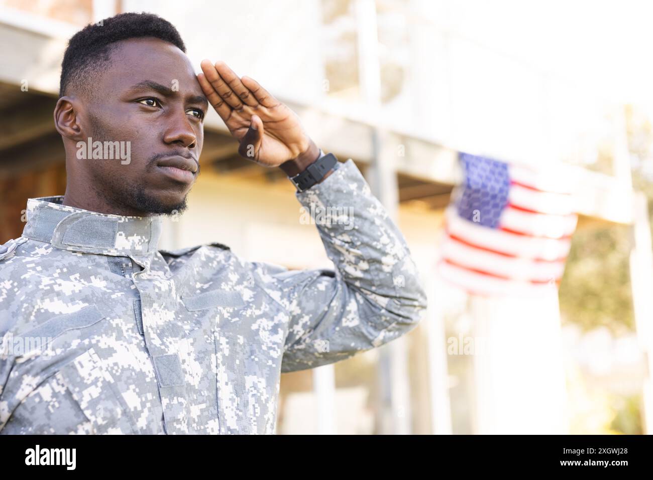 Focused african american male soldier in uniform saluting outdoors ...