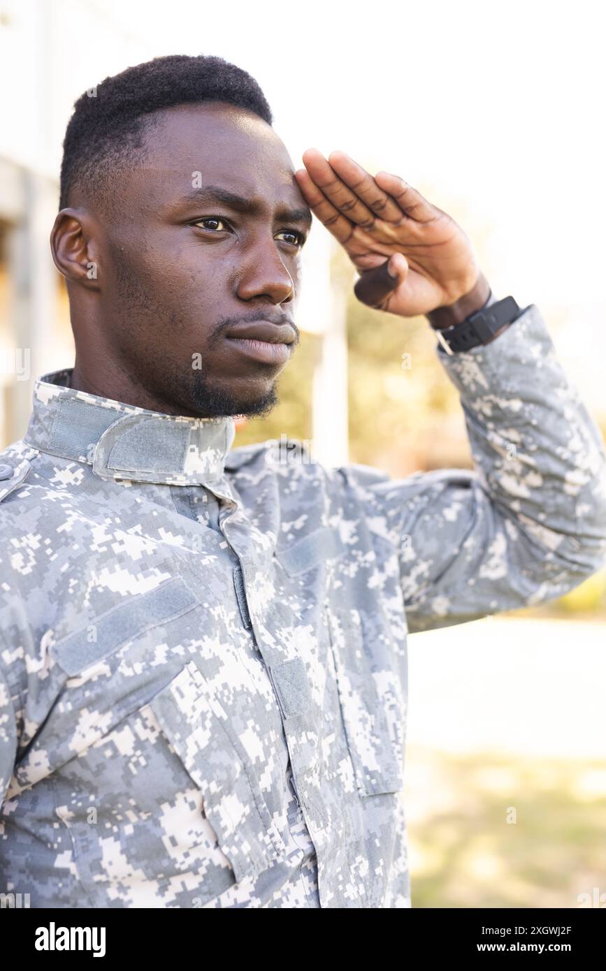 Focused african american male soldier in uniform saluting outdoors ...