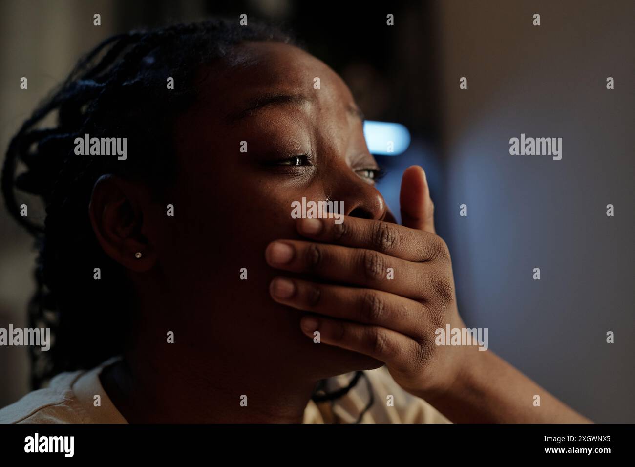 Young crying woman covering her mouth by hand while expressing ...