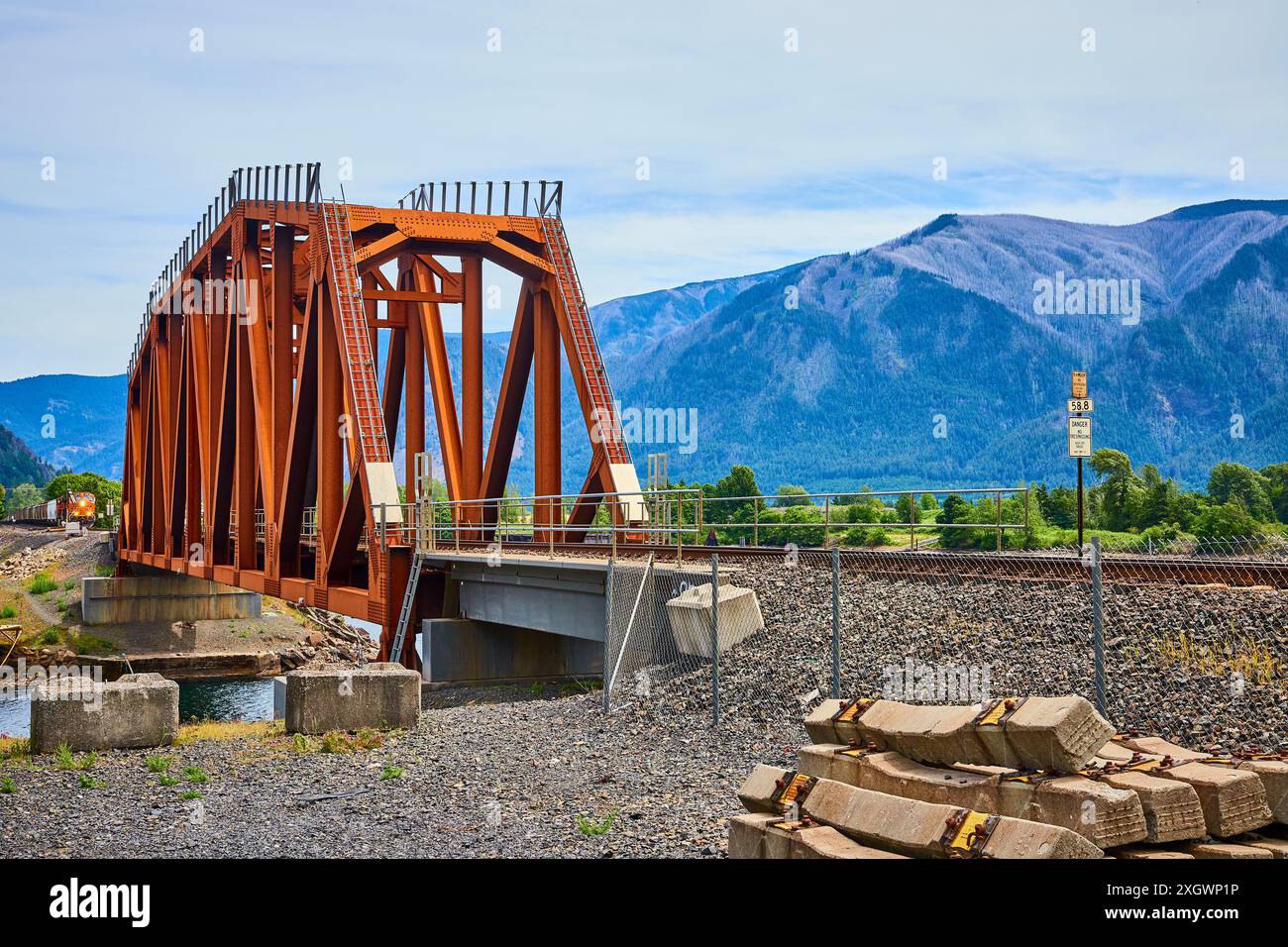 Train Crossing Orange-Brown Truss Bridge Over River in Scenic Mountain ...