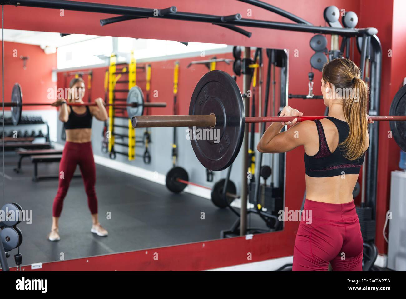 Fit young Caucasian woman lifting weights at the gym. Her focused ...