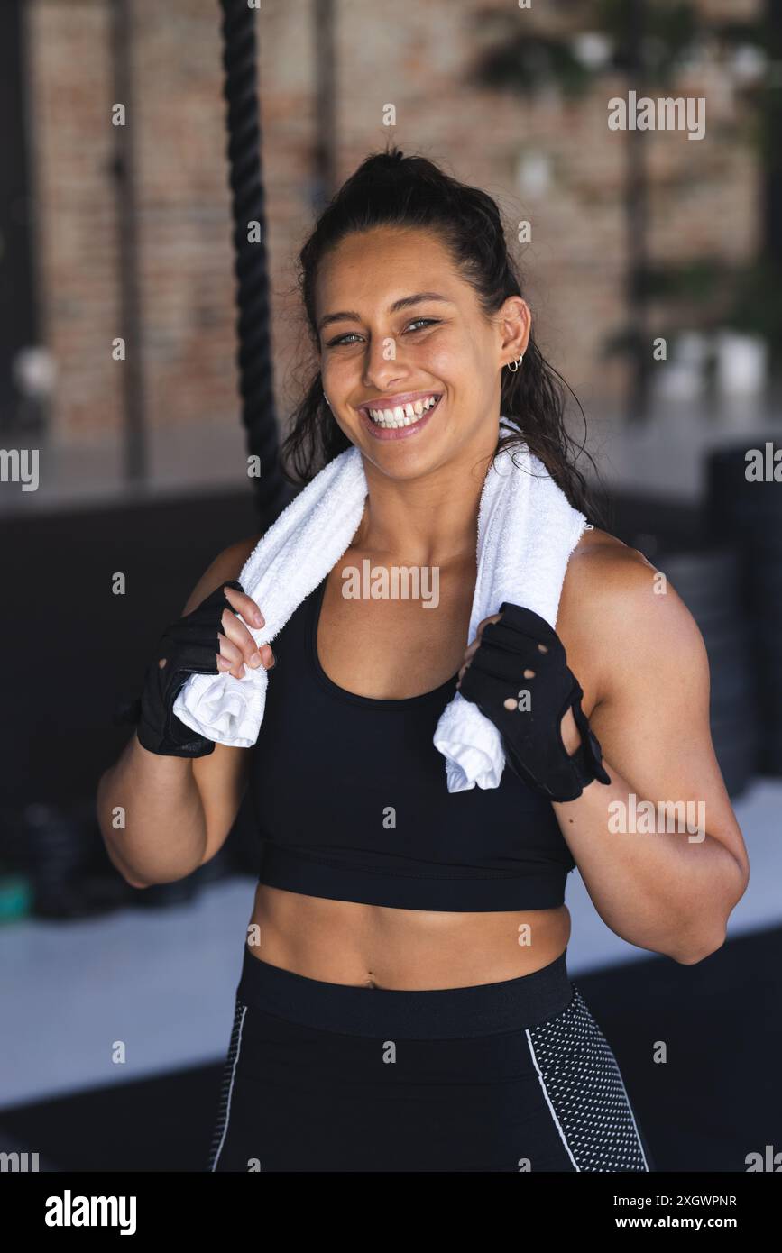 A fit young biracial woman smiles post-gym workout. Her sporty attire ...