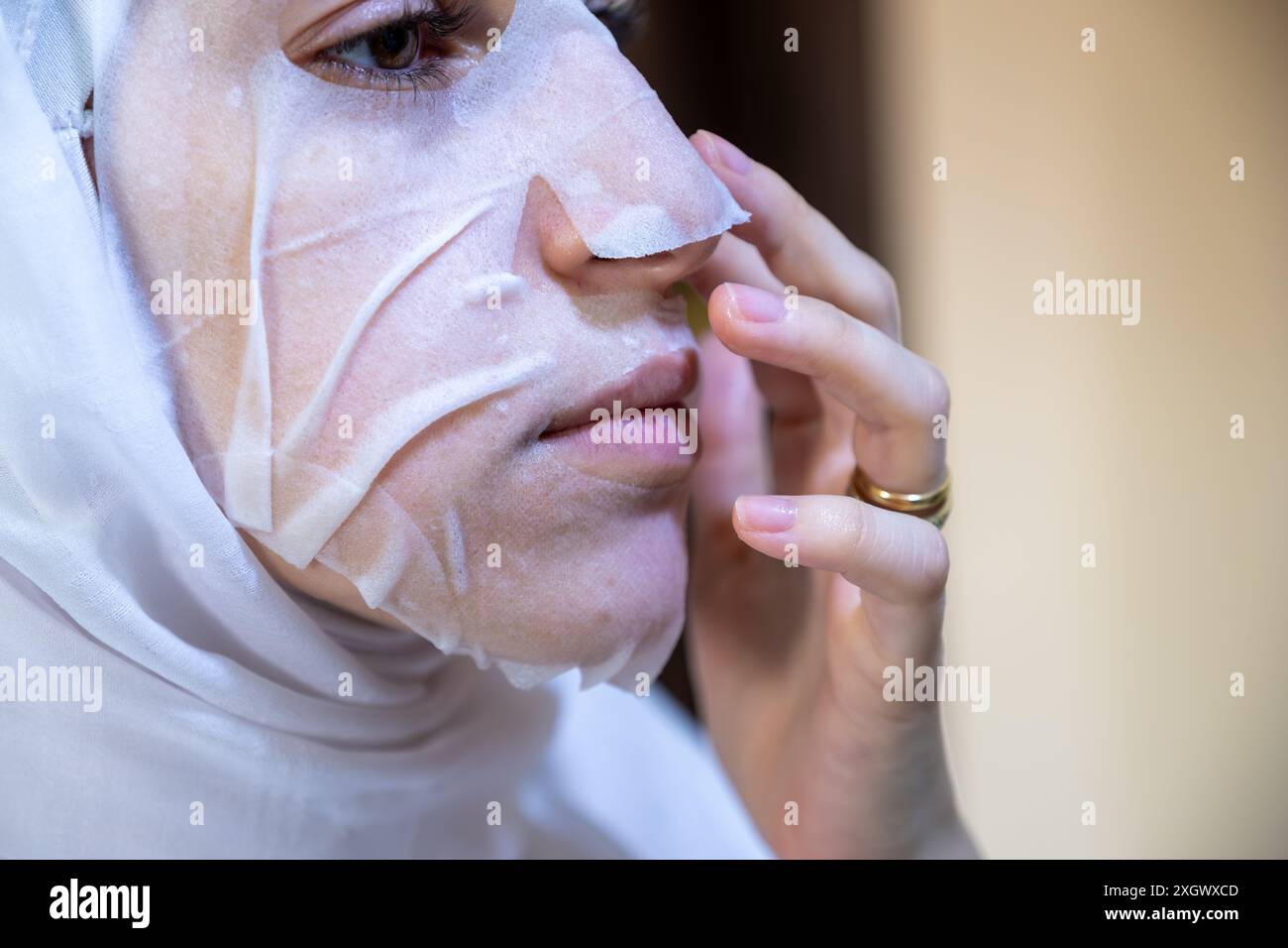 Arabic muslim female wearing hijab applying facial mask in spa or bath ...