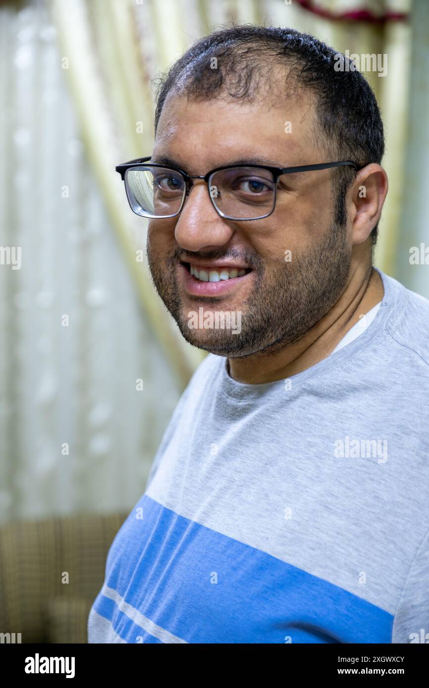 Man in glasses, smiling and relaxed at home, captured in candid ...